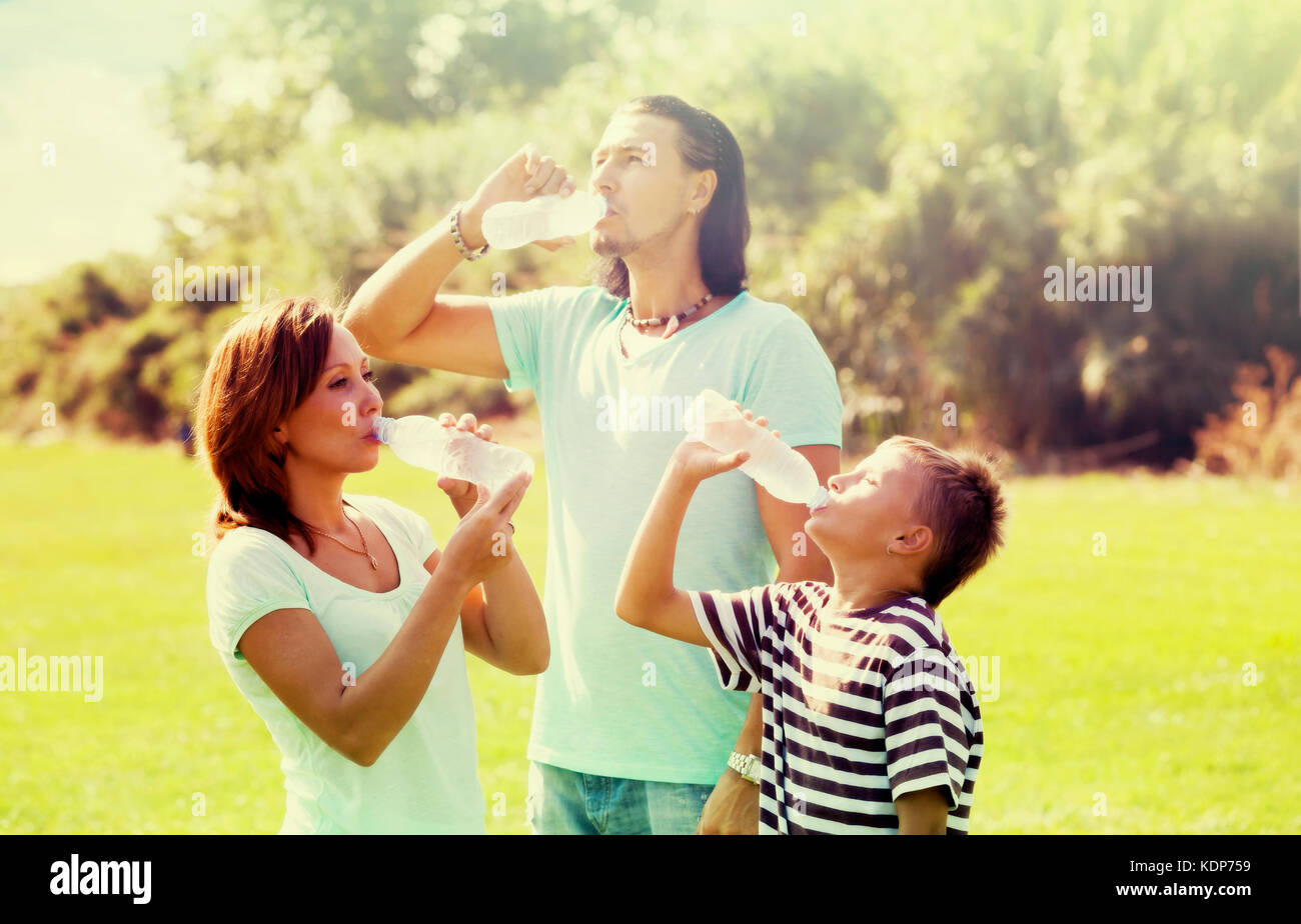 parents with teenager son drinking clean water from plastic bottles in ...