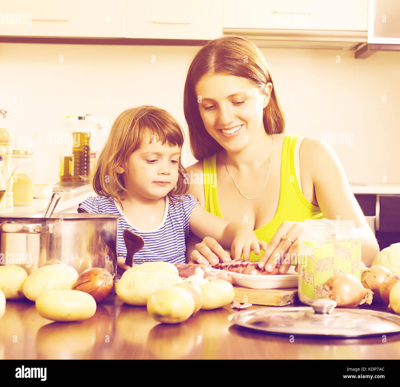Happy woman with baby cooking with meat and vegetables together Stock ...