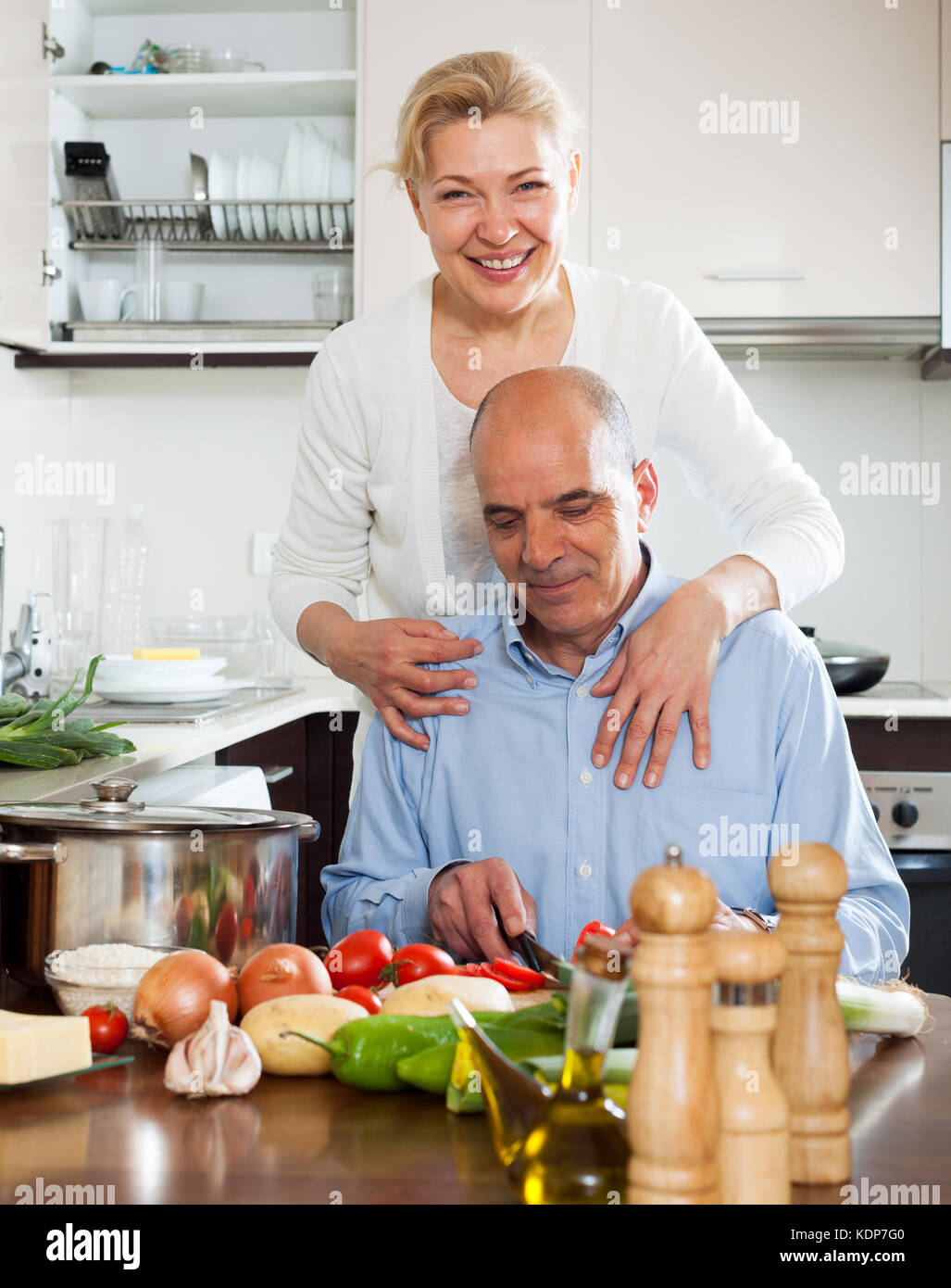 Happy vegetarian couple smiling and cooking vegetables at home kitchen ...