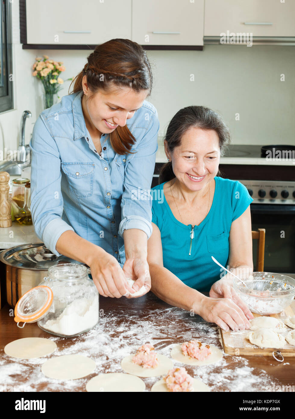 laughing women making pies or meat dumplings at home kitchen Stock ...
