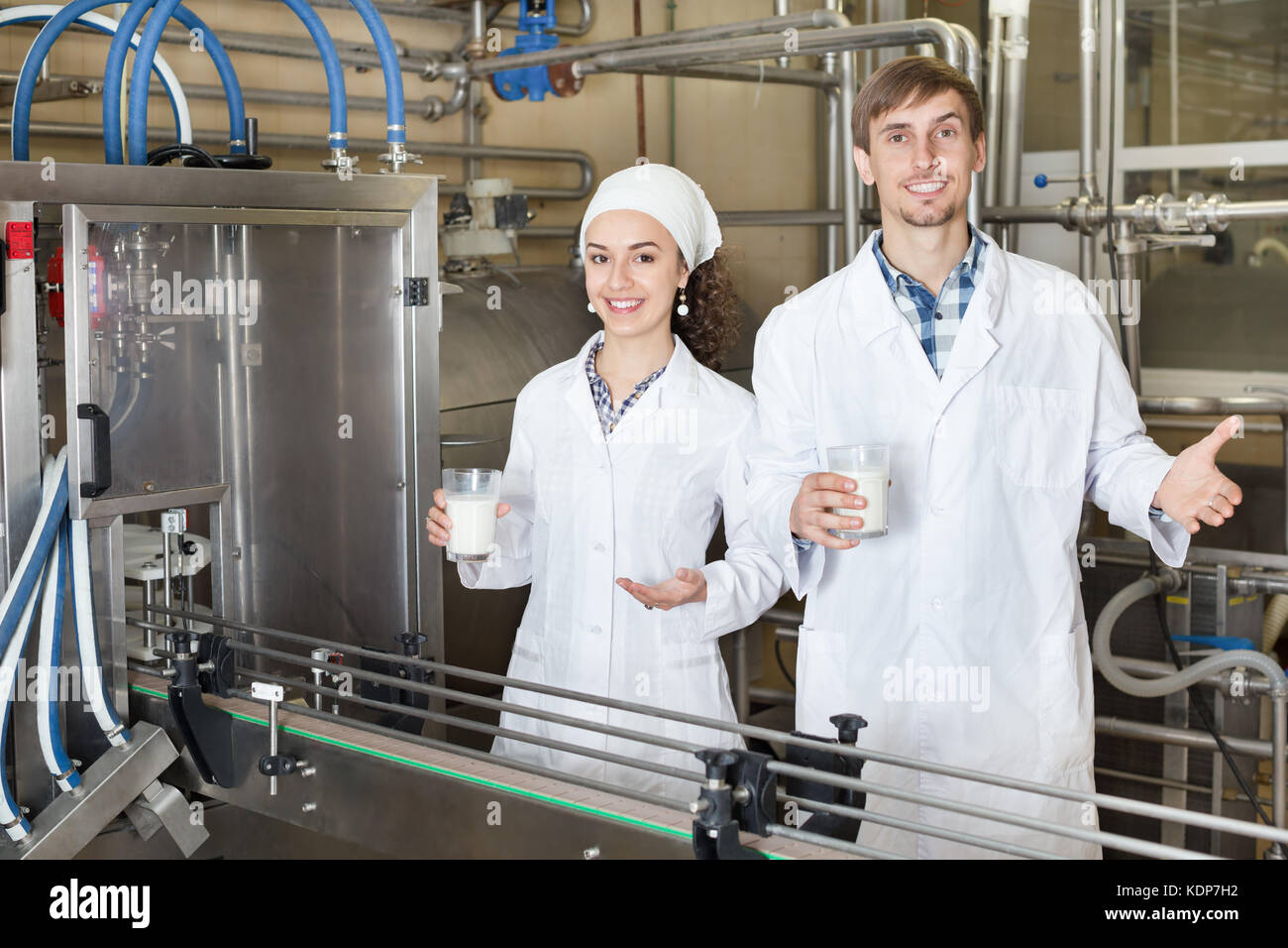 Two smiling workers in lab coats showing their dairy production process ...