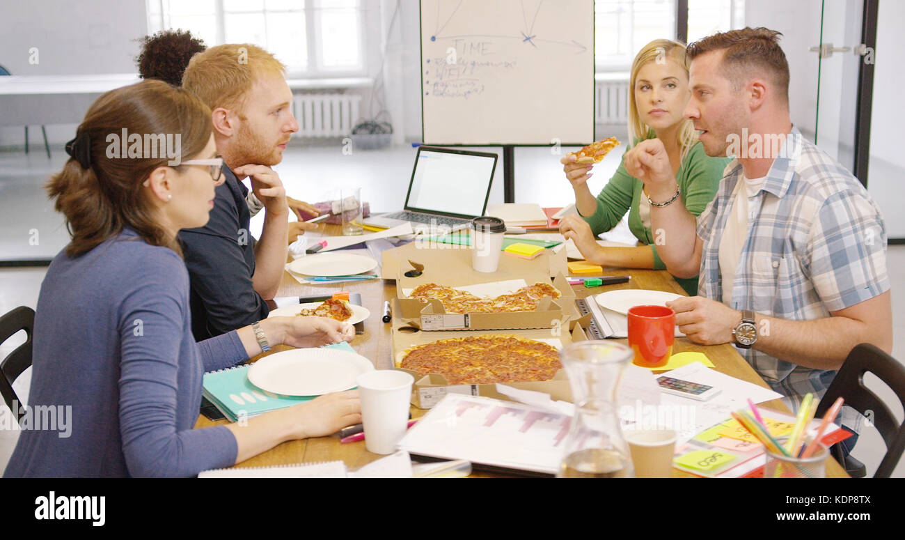 Young people enjoying pizza in office Stock Photo - Alamy