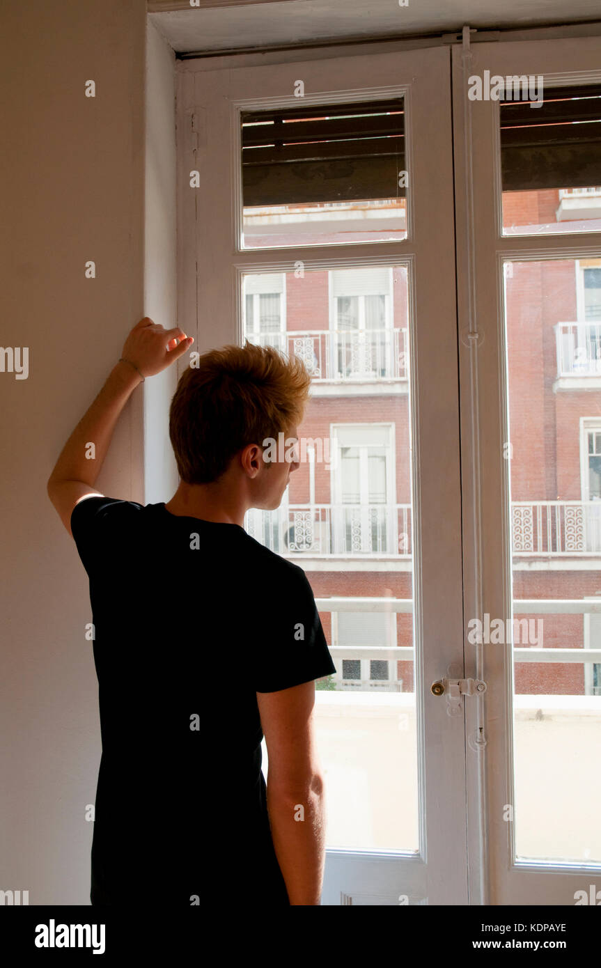 Young man looking through the window Stock Photo - Alamy