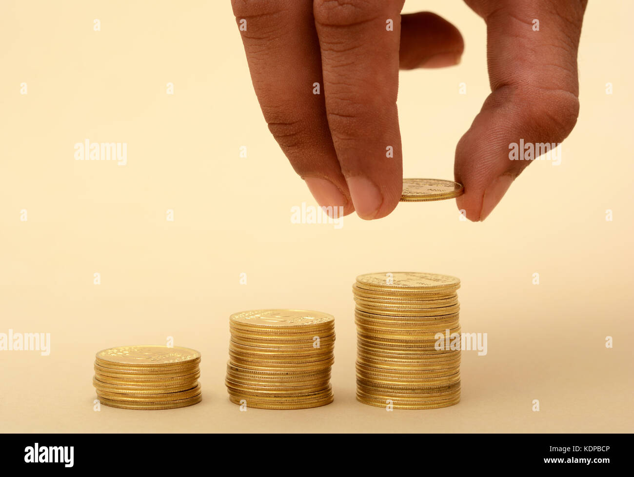 Professional Hand Putting on Stack of Golden Coins Stock Photo - Alamy