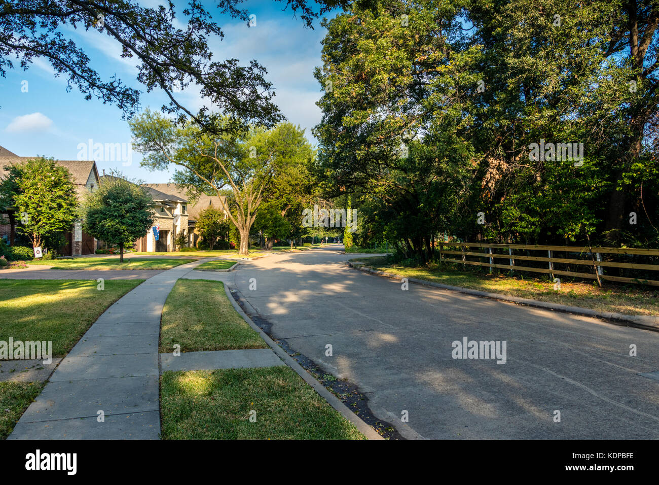 Quiet Neighborhood street with trees and fence on summer morning Stock ...