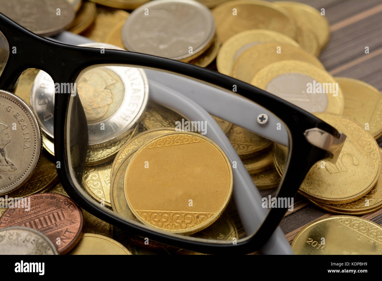 Eye Glass with gold coins closeup - Analysis concept Stock Photo - Alamy