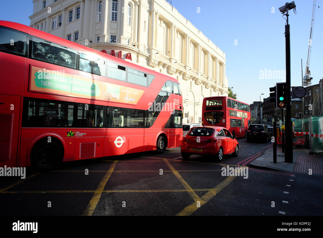 Red double decker buses crossing a box junction and CCTV camera in ...