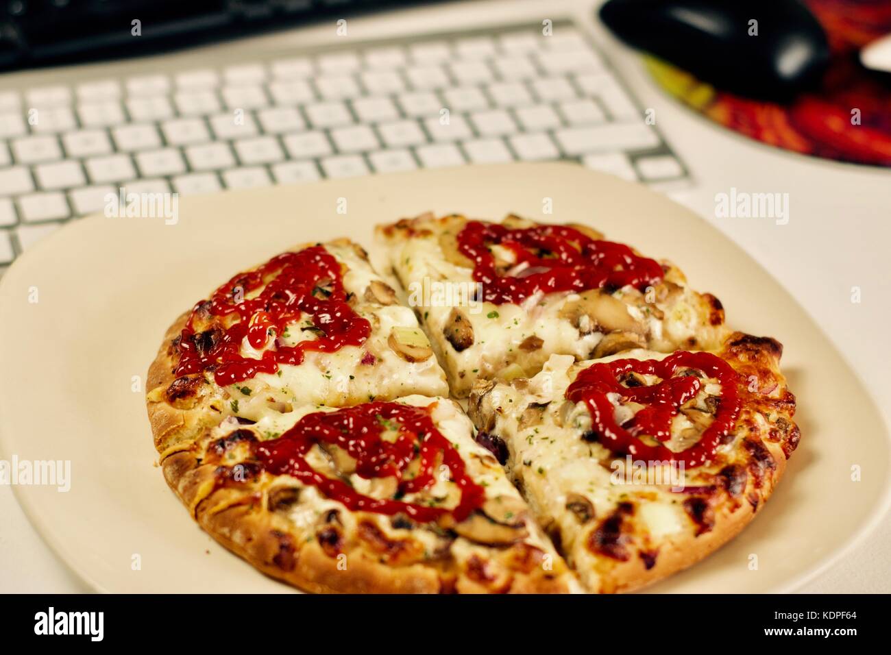 Fresh and tasty pizza near computer white keyboard. Red ketchup concept ...