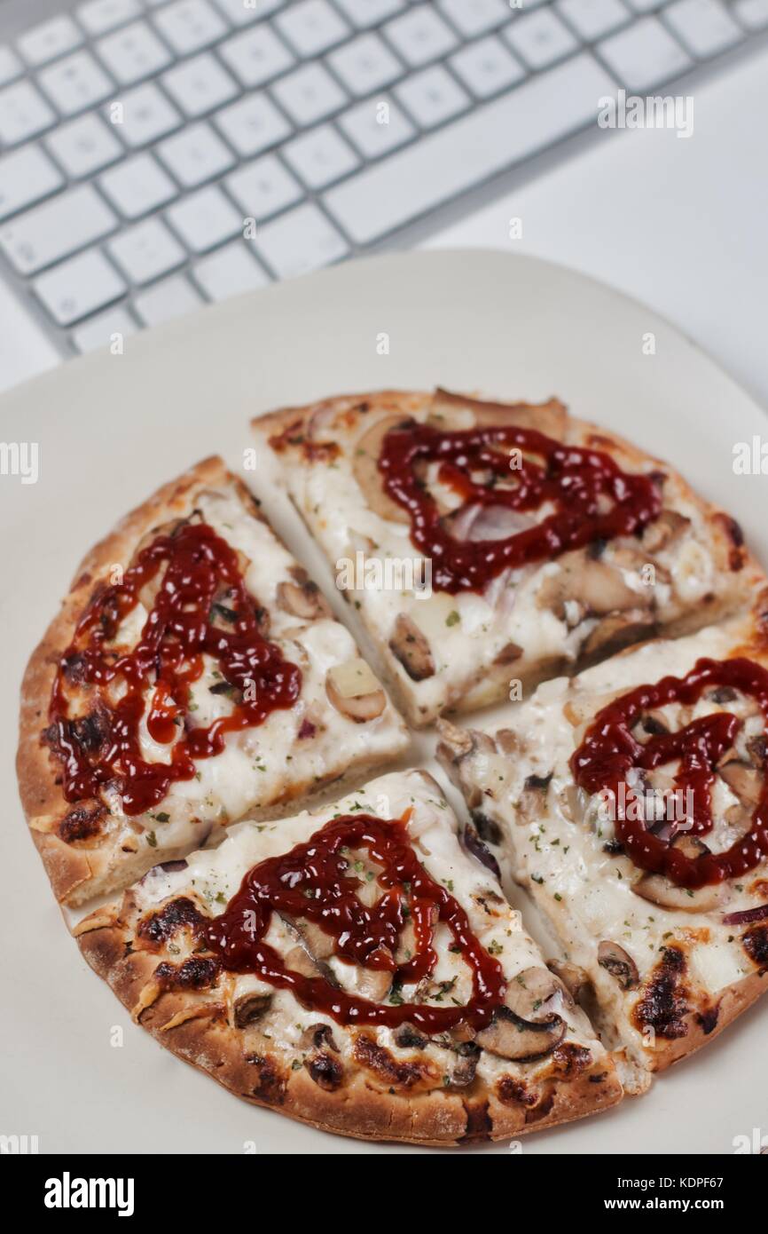 Fresh and tasty pizza near computer white keyboard. Red ketchup concept ...