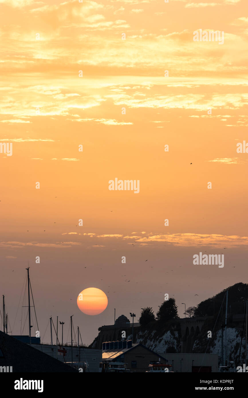 England, Ramsgate. Sunset over Ramsgate seen from the harbour. Sun is ...