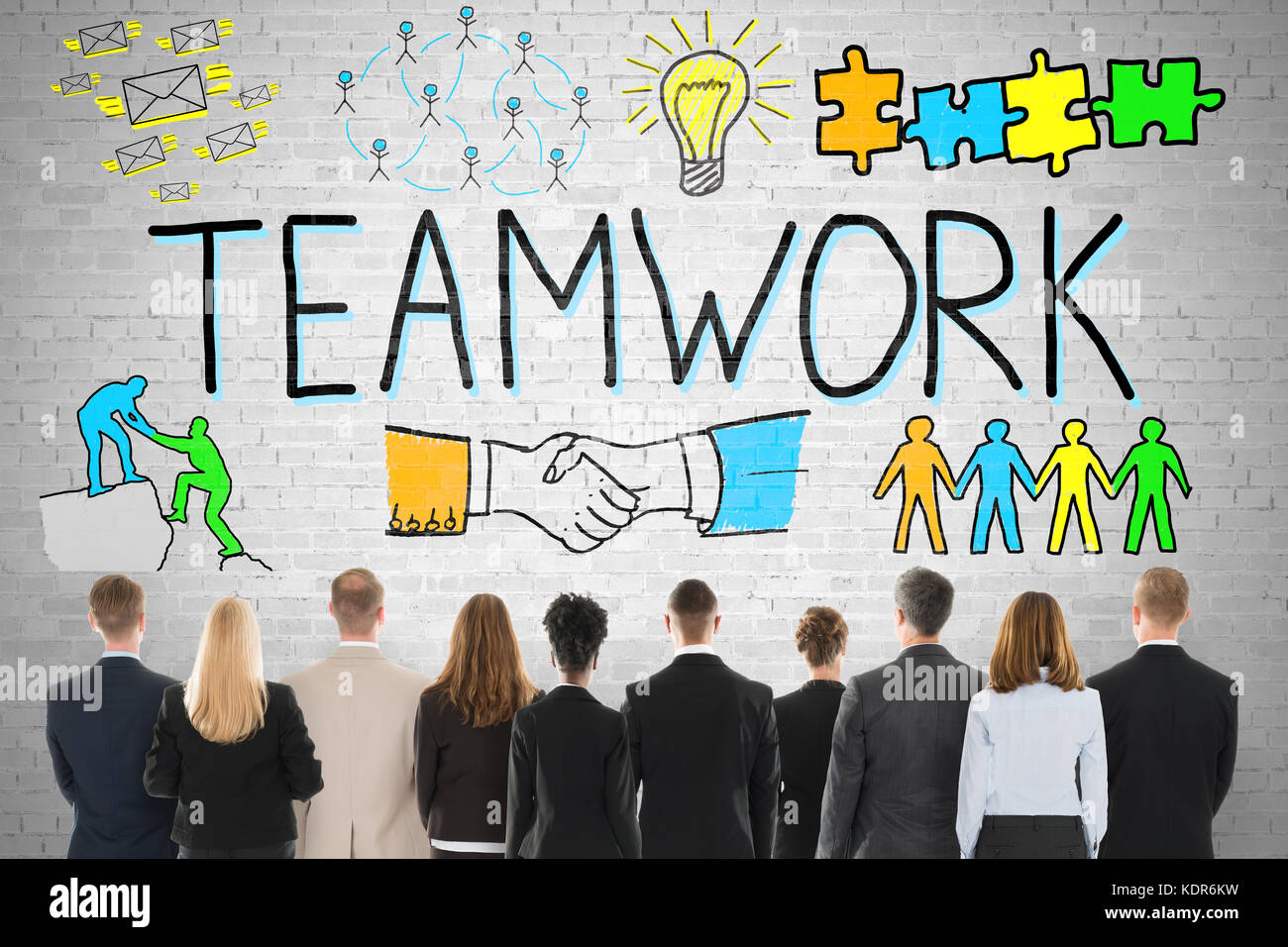 Rear View Of Businesspeople Looking At Teamwork Concept On Brick Wall ...
