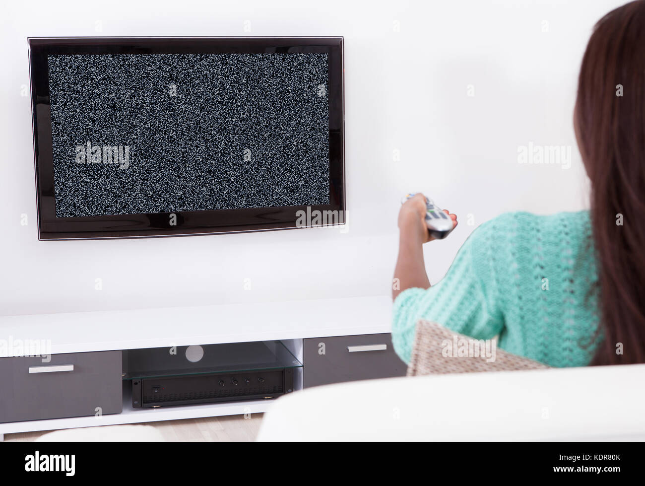 Woman Sitting On Couch With Remote Control Watching Television Showing ...