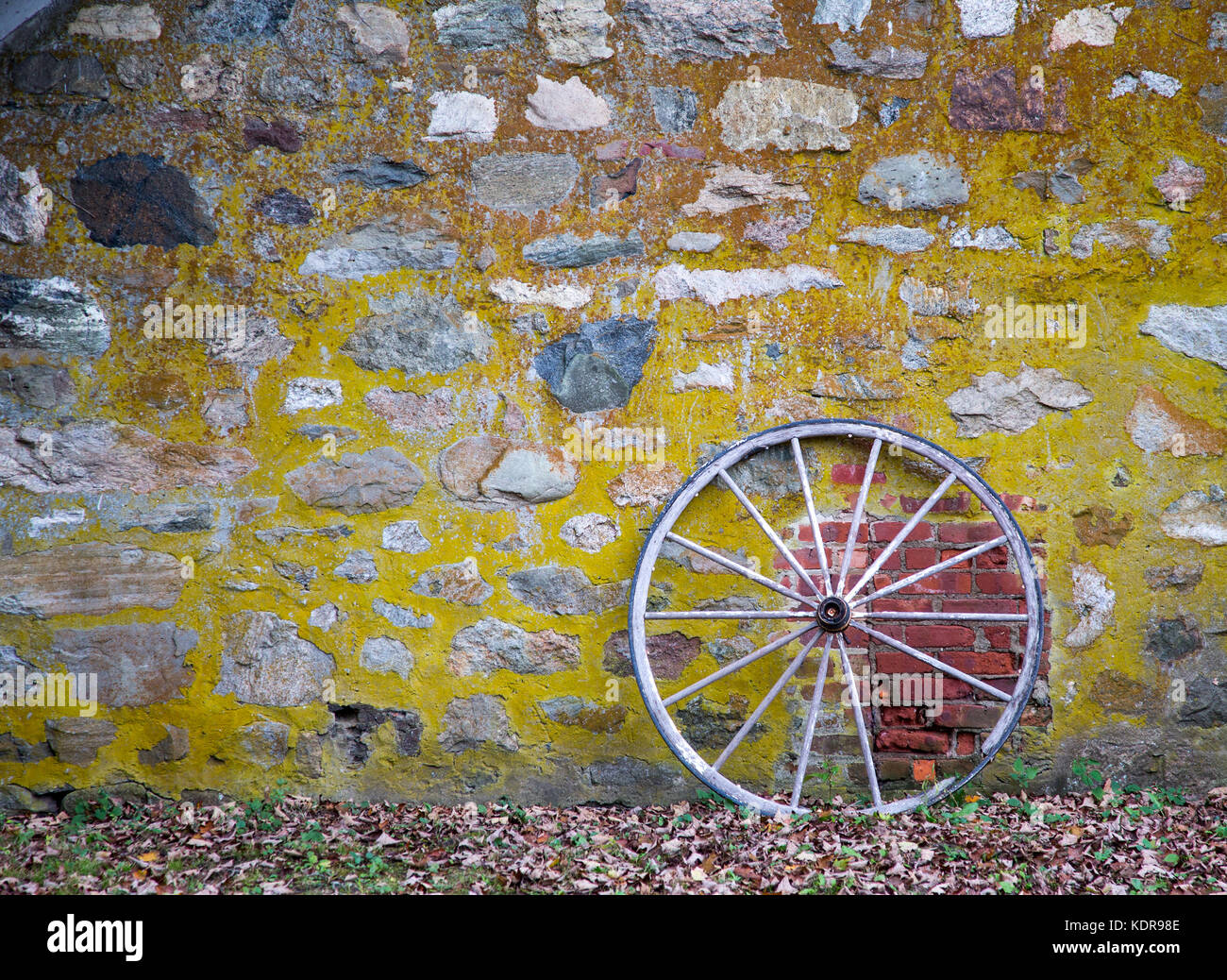 An old wooden wheel against a stone wall at the Ringwood Manor in New ...