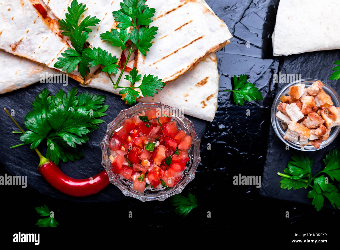 Mexican quesadilla and ingredients with salsa on black slate stone ...