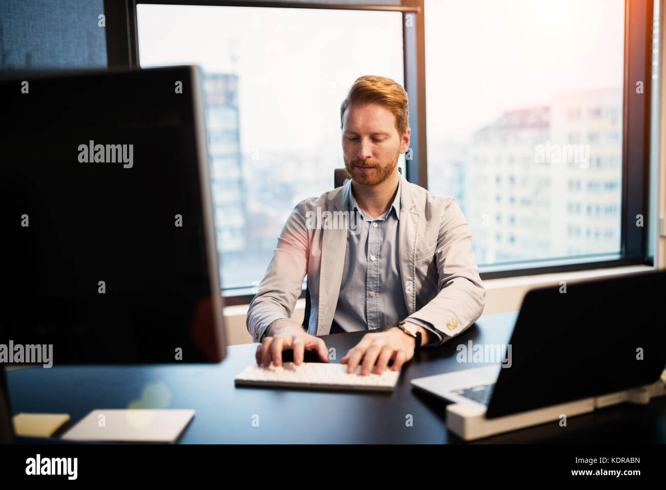 Handsome young businessman working on computer in office Stock Photo ...