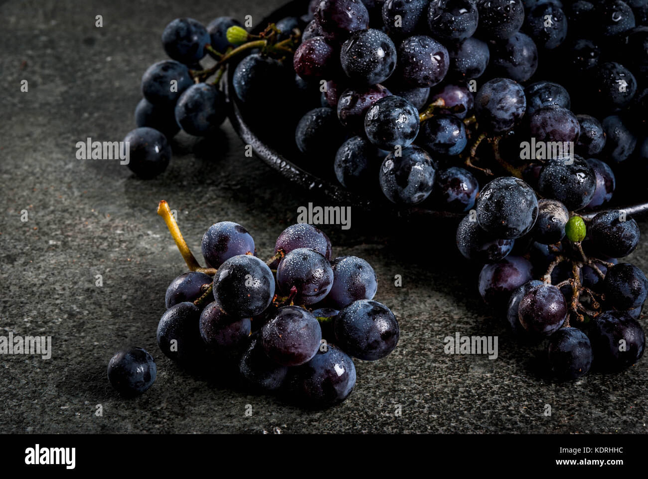 Raw natural organic farmer's black grapes, bunches on black plate, dark ...