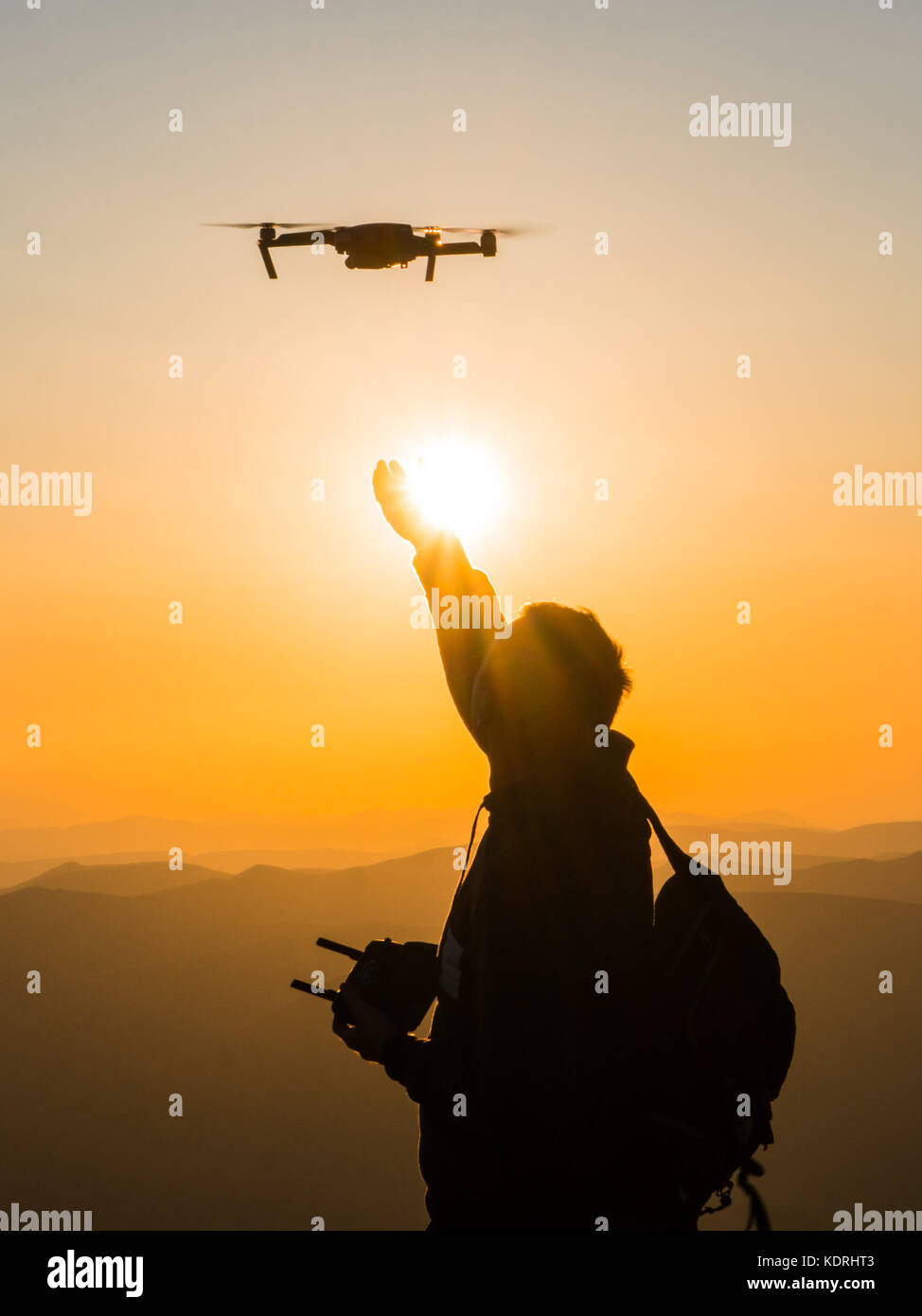 Silhouette of young man catching drone at sunset for photos and video ...