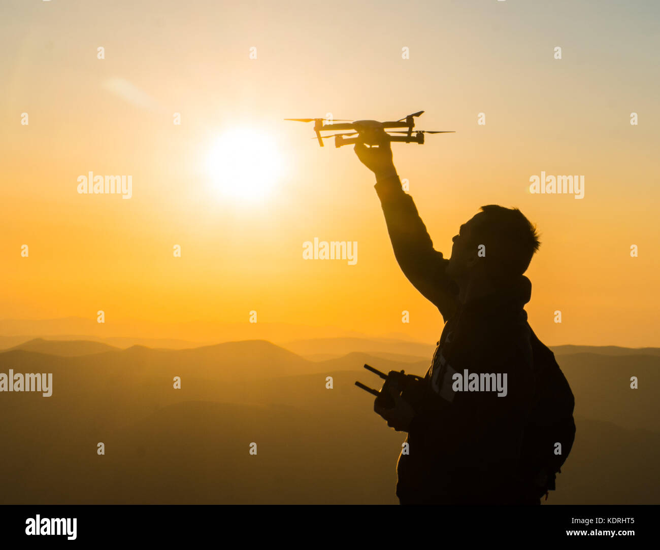 Silhouette of young man keeping drone at sunset for photos and video ...