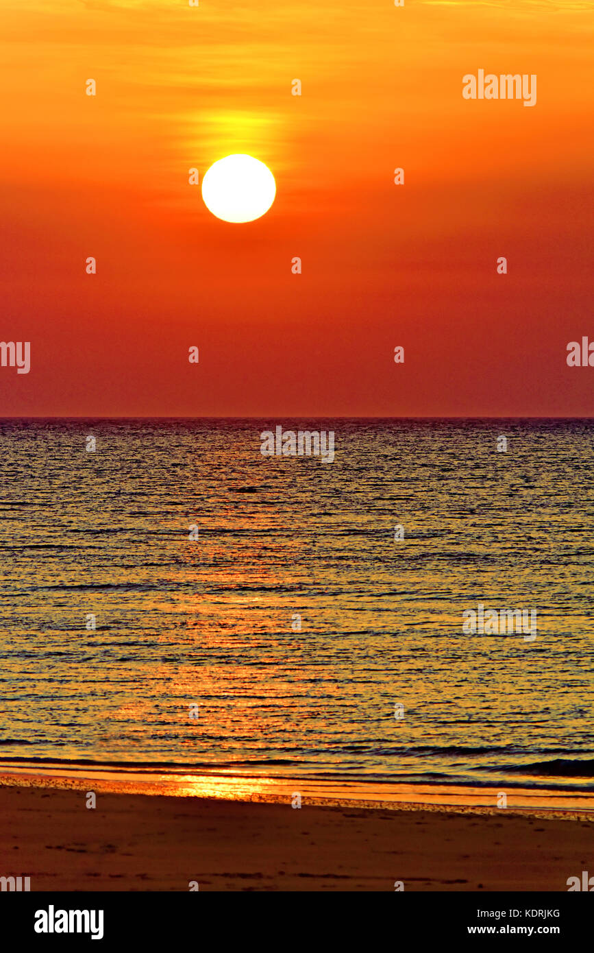 Sunrise with large sun and sandy beach Stock Photo - Alamy