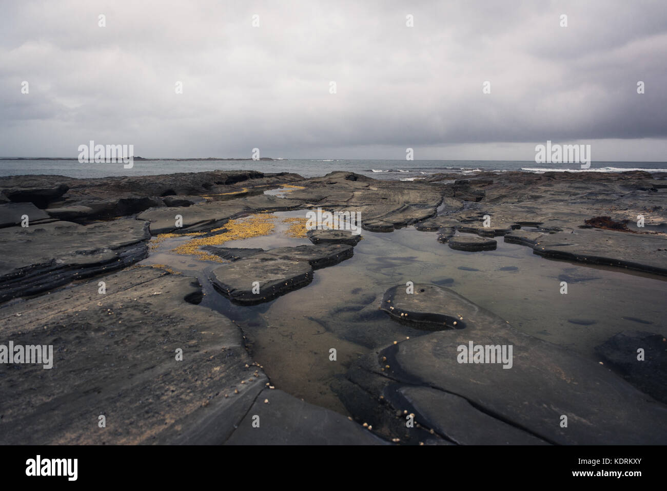 flat rock formation on the oceans edge with water at sunset Stock Photo ...