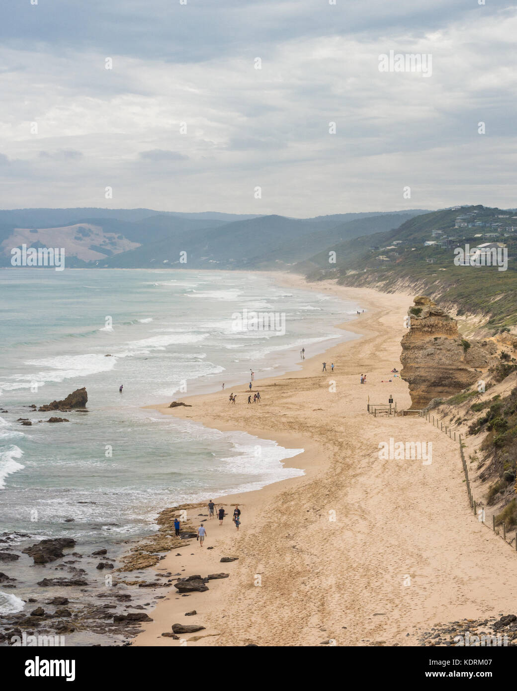 Aerial view looking down a long sandy beach with tall cliffs and gentle ...