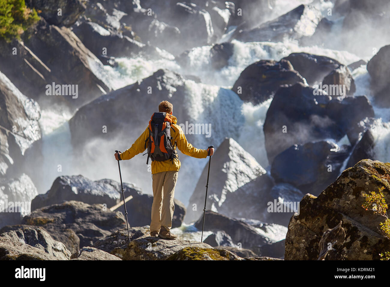 Hiker hiking with backpack looking at waterfall Stock Photo - Alamy