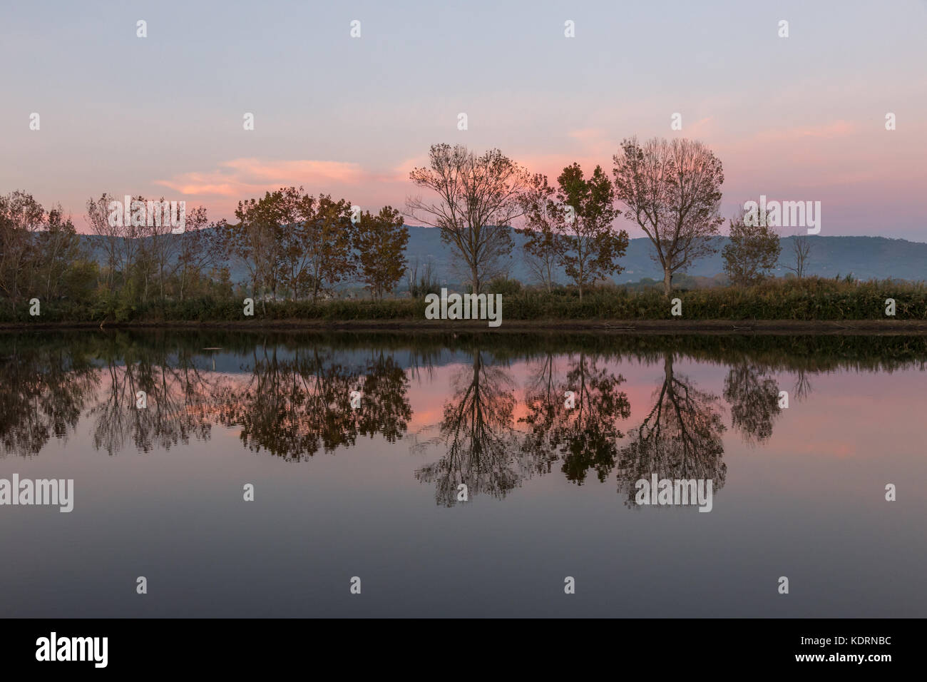 A symmetric photo of a lake, with trees and clouds reflections on water ...
