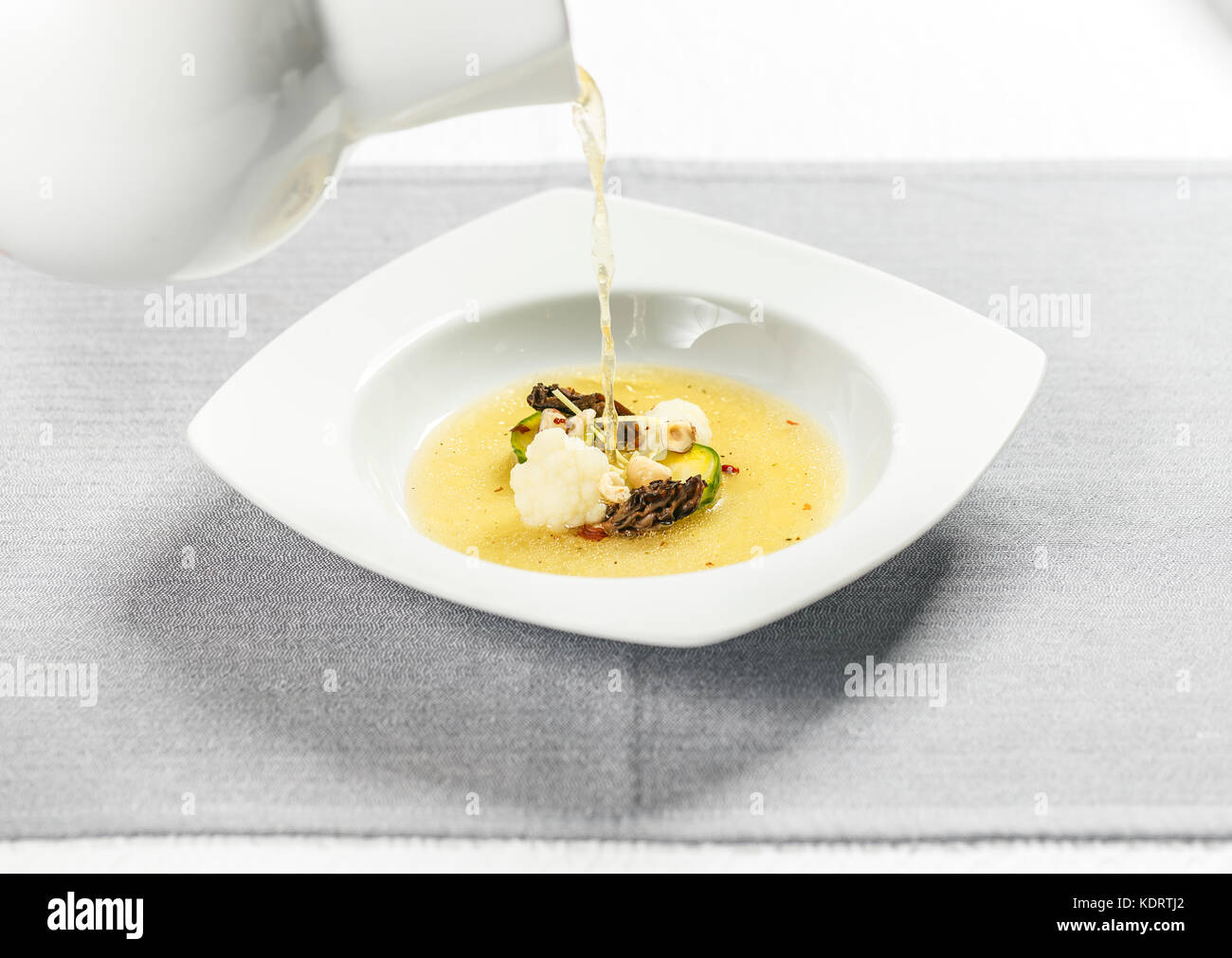 Pouring clear soup into a white plate Stock Photo - Alamy