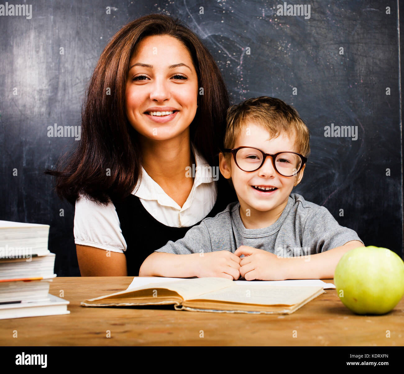 little cute boy in glasses with young real teacher, classroom studying ...