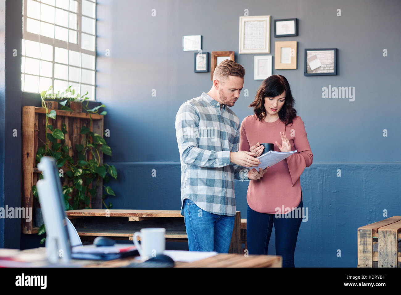 Two focused work colleagues discussing paperwork together in an office ...
