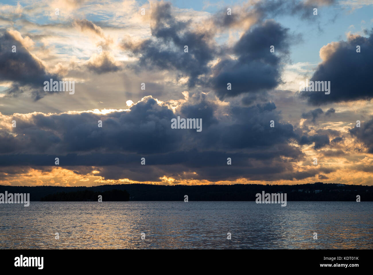 View of dark and dramatic clouds, rays of light and a lake in Finland ...