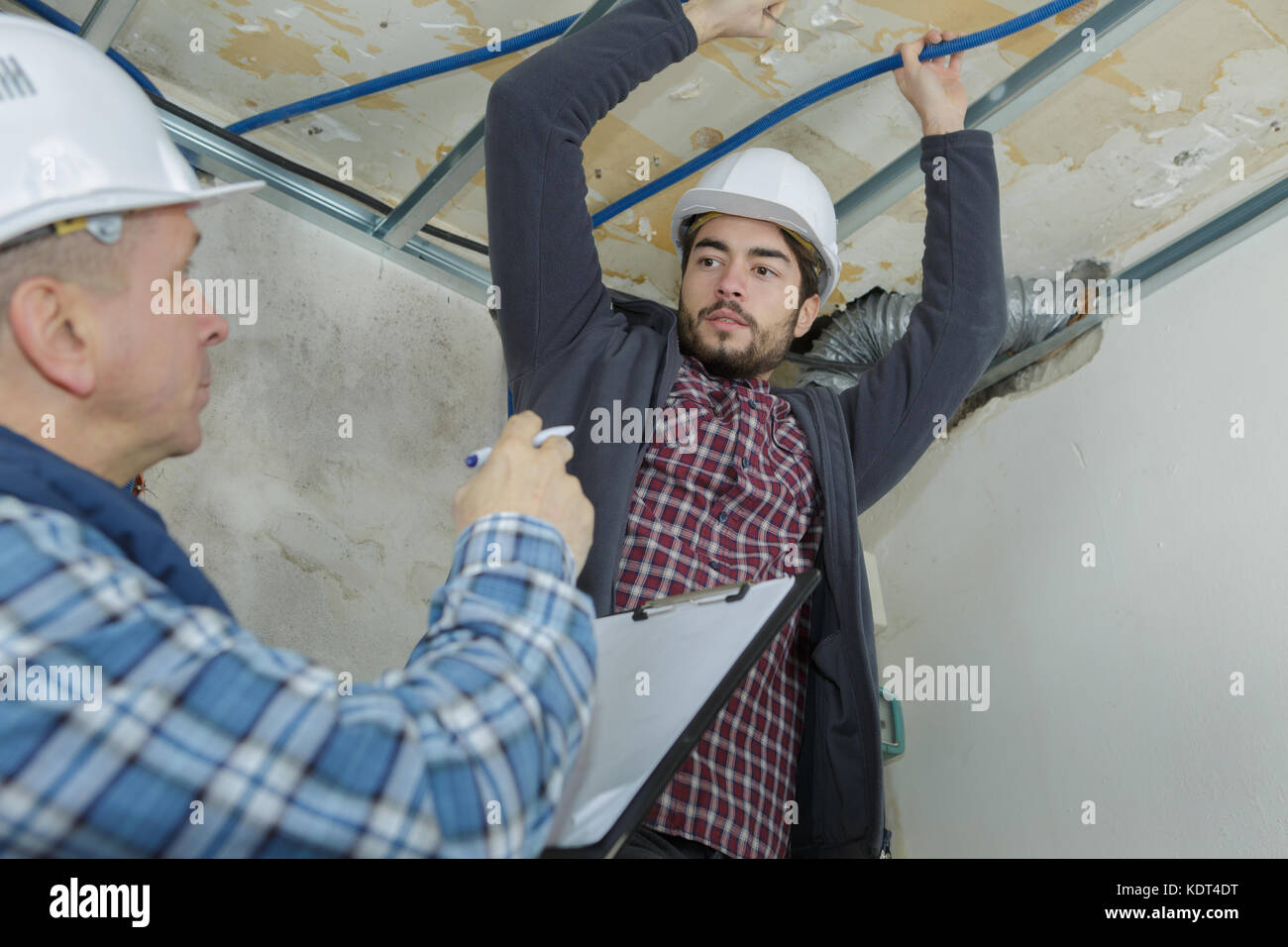 Contractor fitting overhead pipework Stock Photo - Alamy