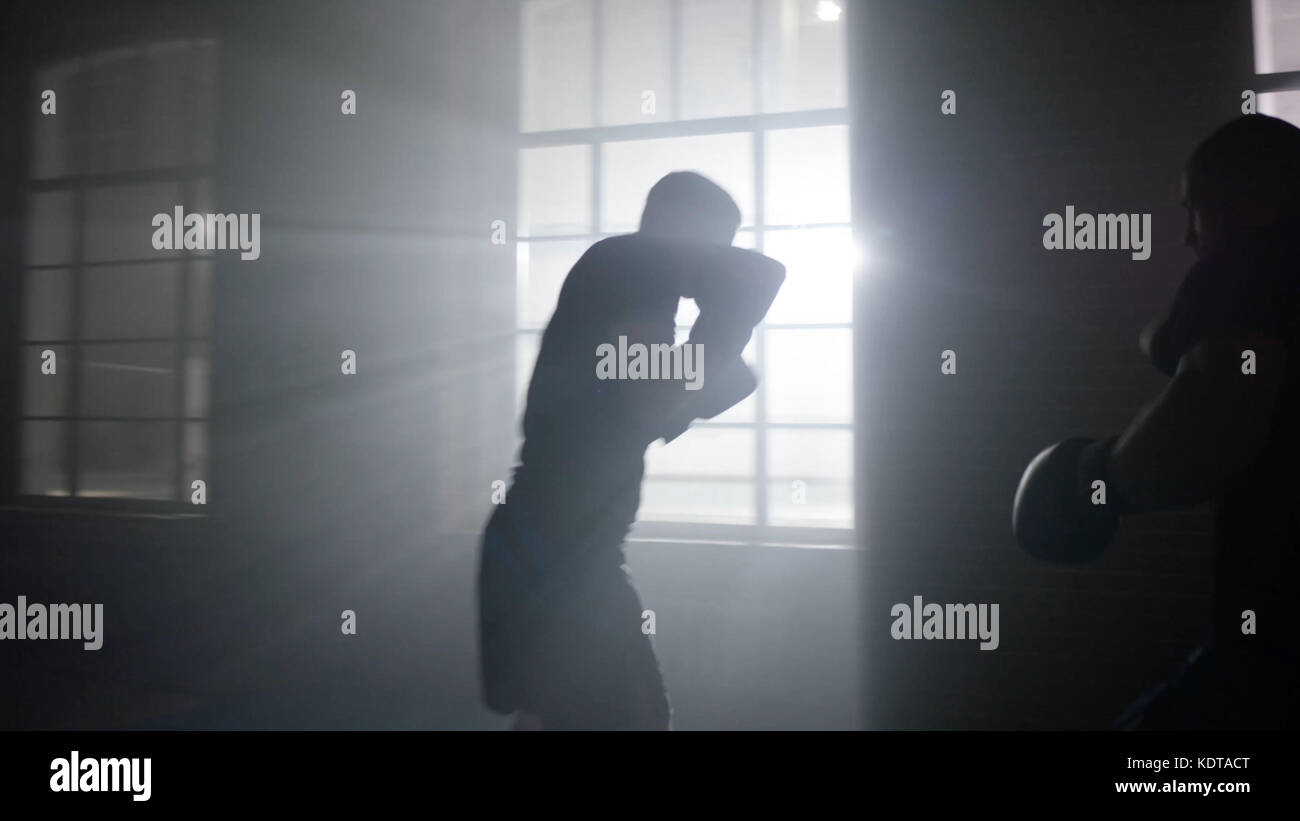 Two boxers train on the ring. Kicking and blocking the hit. One athlete ...