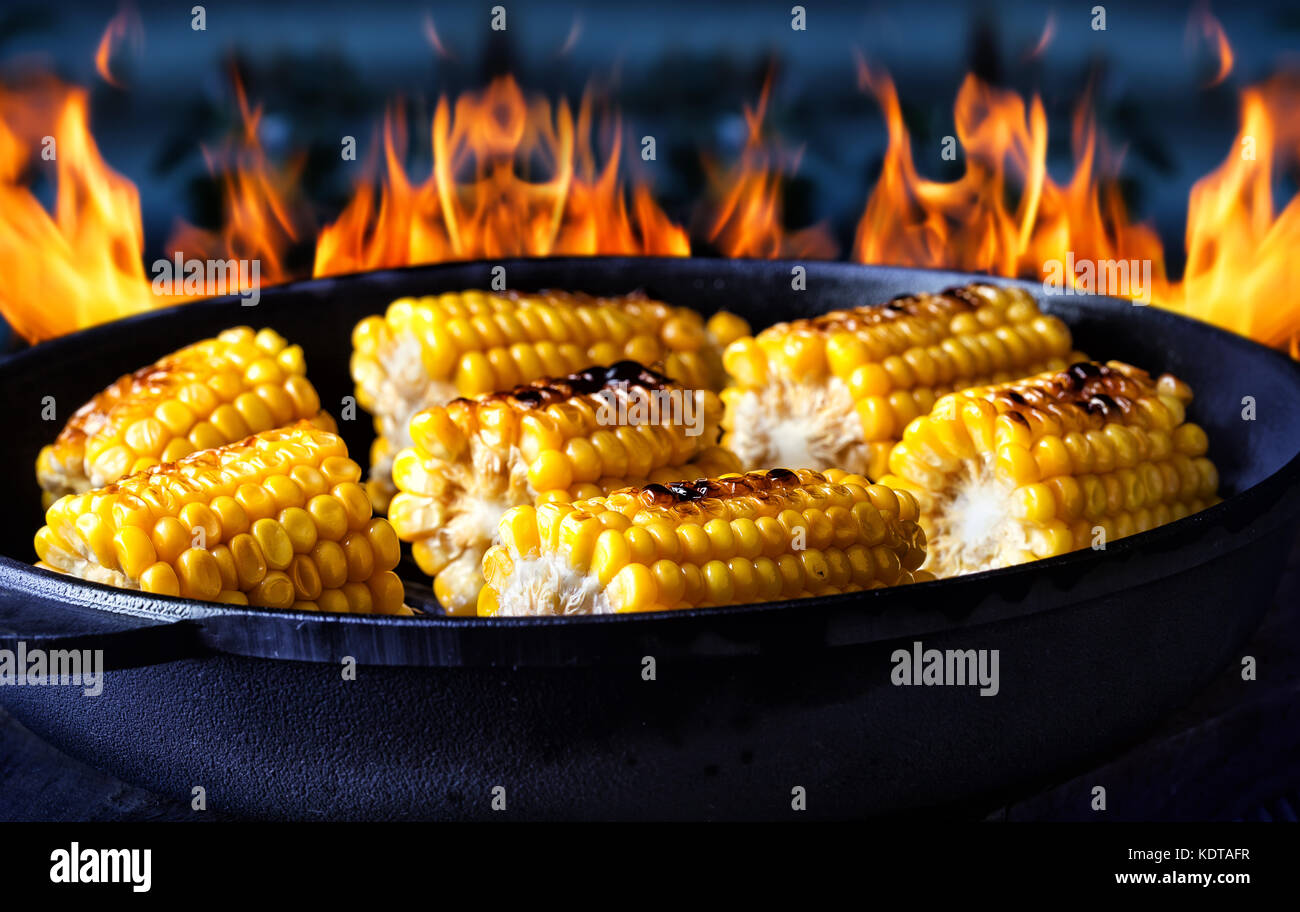 Frying pan with fried corn on fire background Stock Photo - Alamy