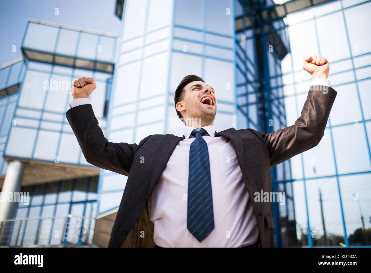 Handsome businessman raising arms in sign of victory Stock Photo - Alamy
