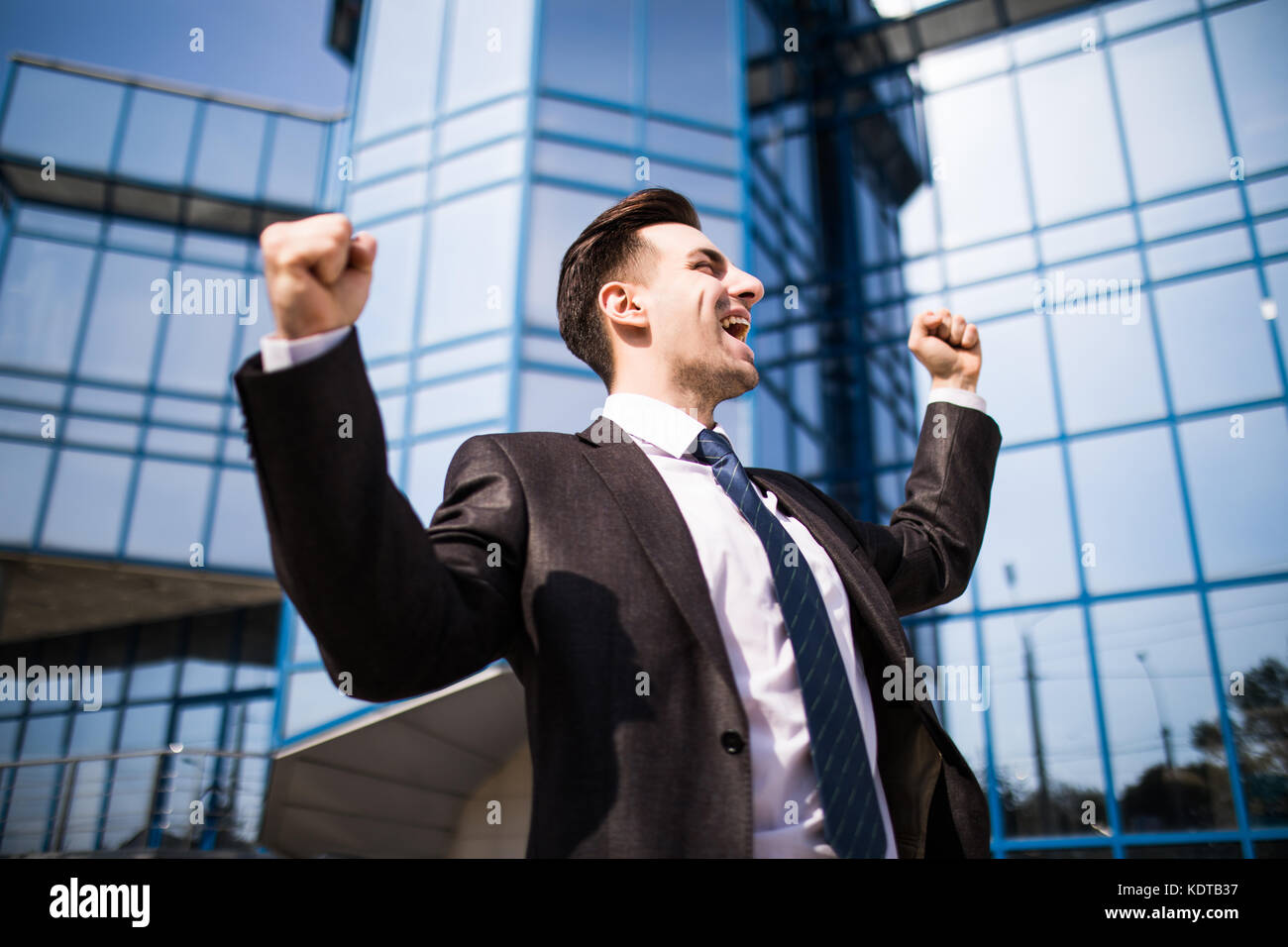 Handsome businessman raising arms in sign of victory Stock Photo - Alamy