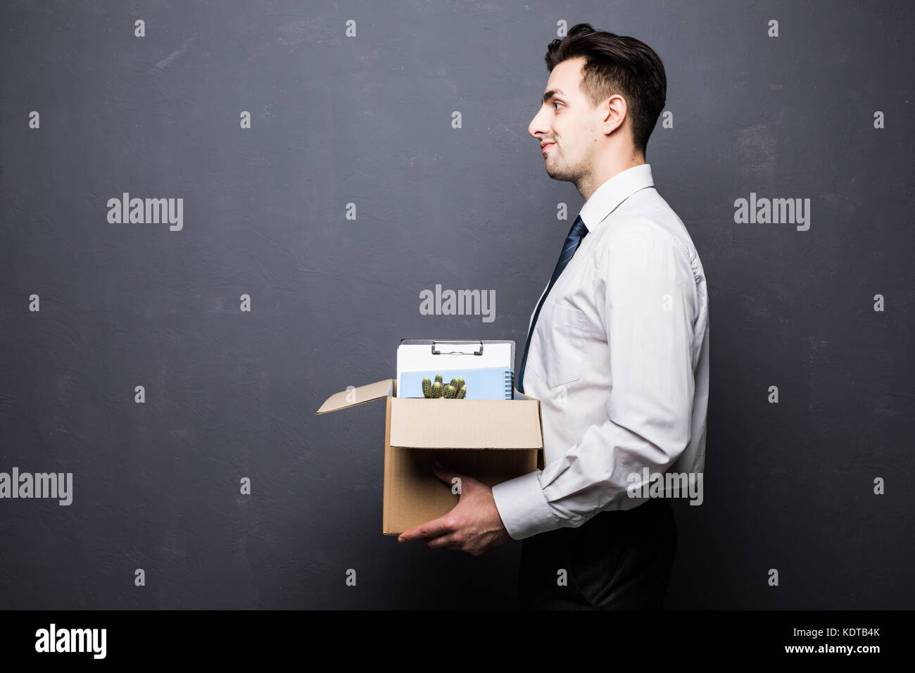 Getting fired. Side view of handsome businessman in formal wear holding ...