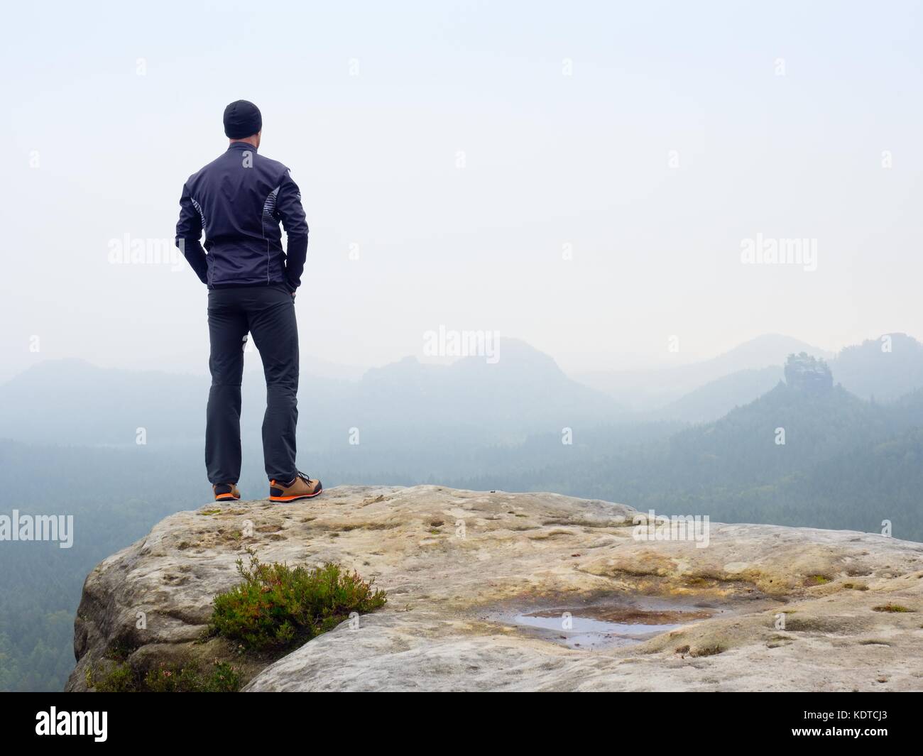 Nature hiker on sharp cliff roc watching over misty valley to blurred ...