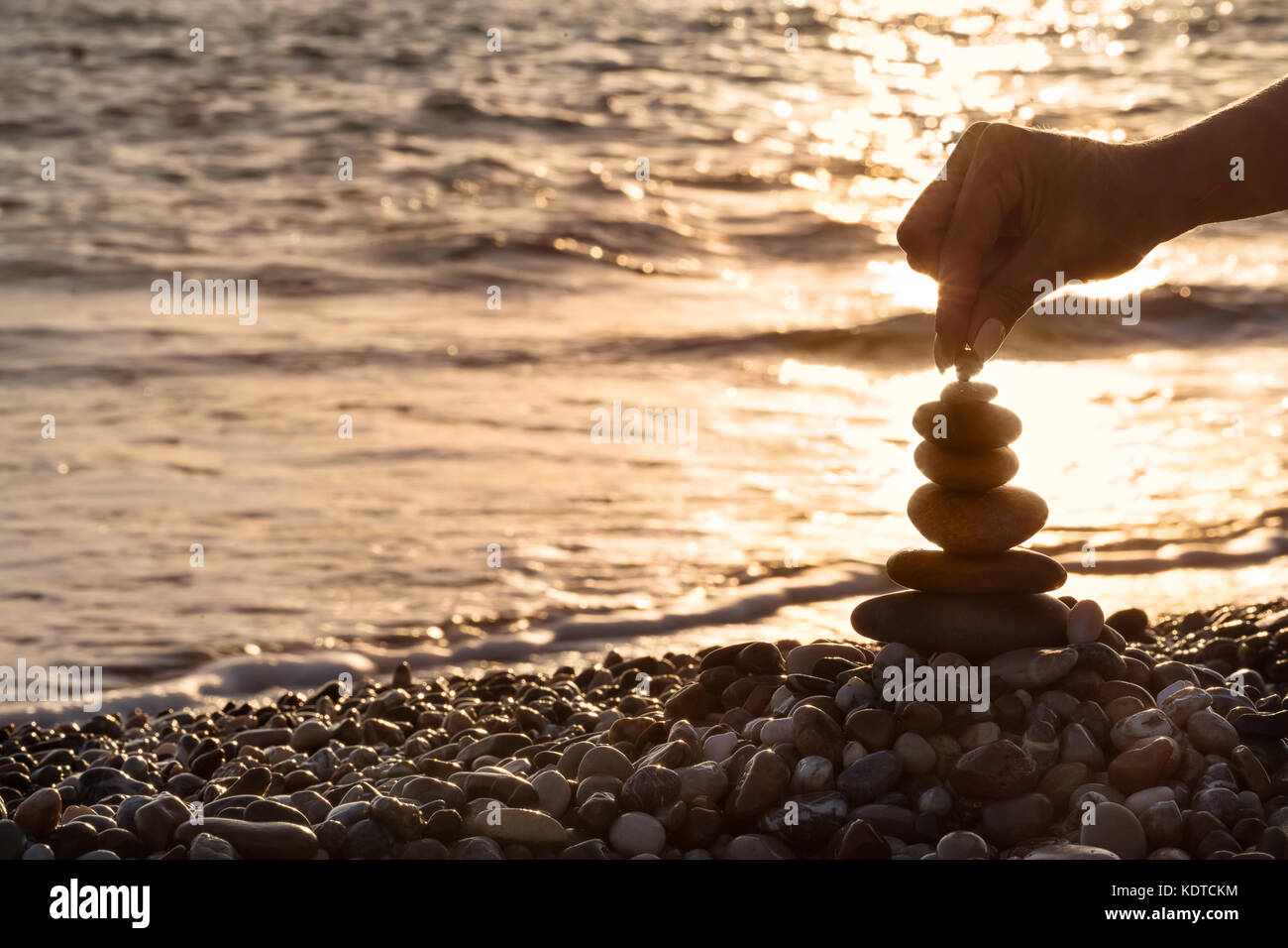 Female hand setting pebble to the top of pyramid Stock Photo - Alamy