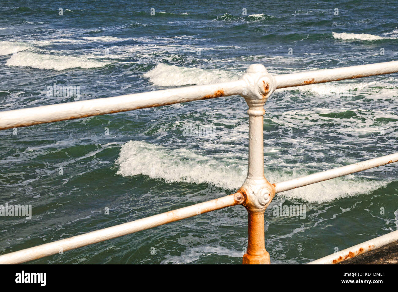 Ocean waves through rusting railings, water background with copy space ...