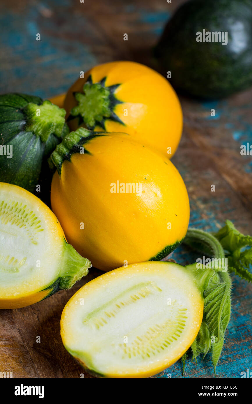 Round yellow courgette or zucchini, on wooden background, close up ...