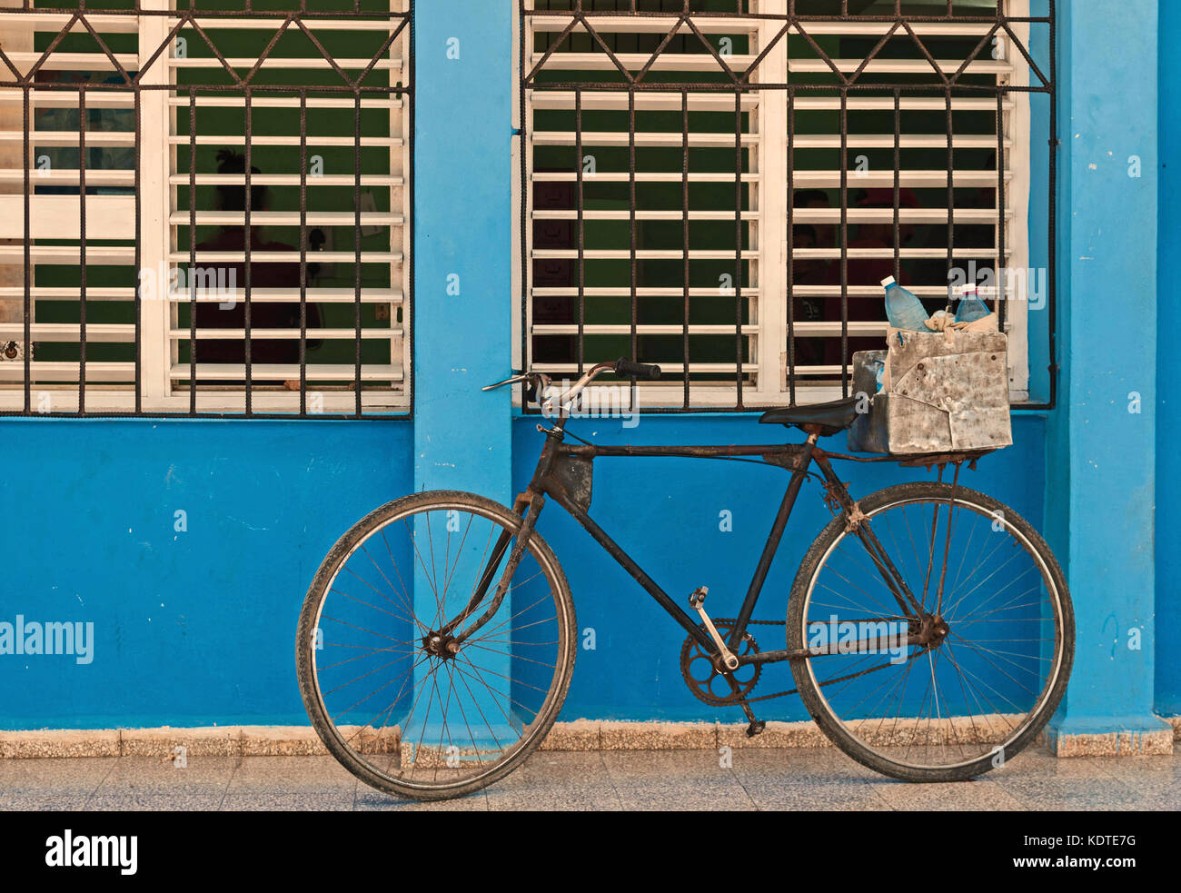 Old bicycle leaning against barred,shuttered windows and blue wall ...