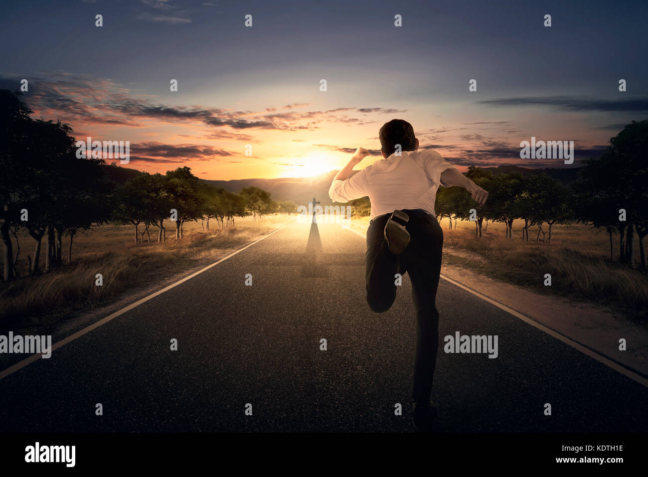 Man running chasing cross at the end of the road at sunset Stock Photo ...