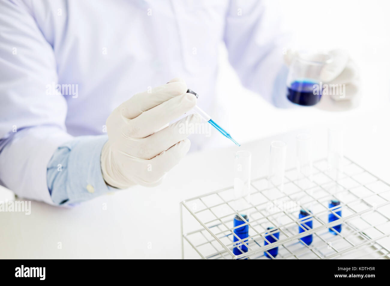 Scientist dropping adds the reagent from the dropper to test tube ...
