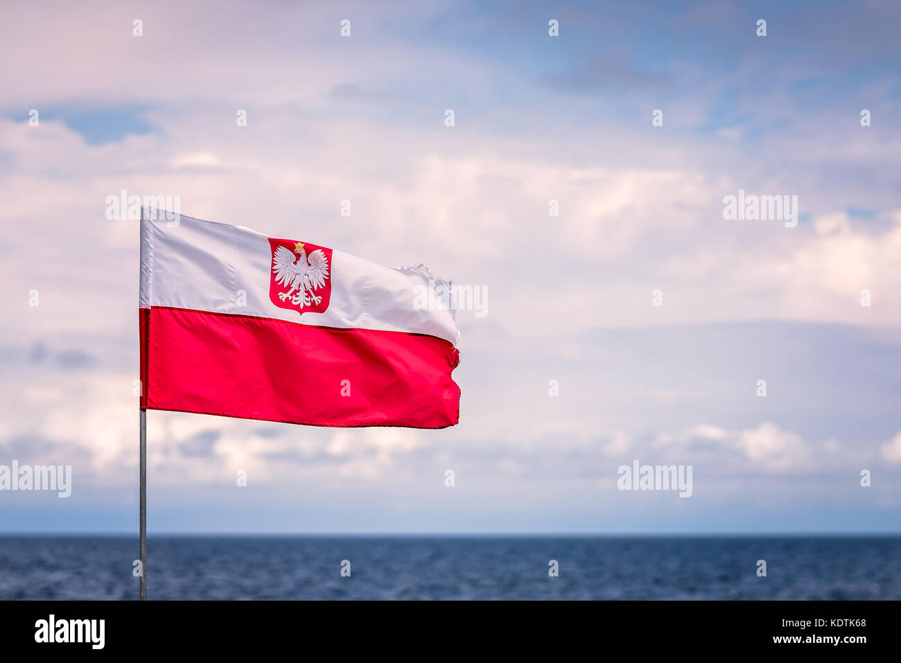 Red and white Polish flag with national eagle emblem fluttering in the ...