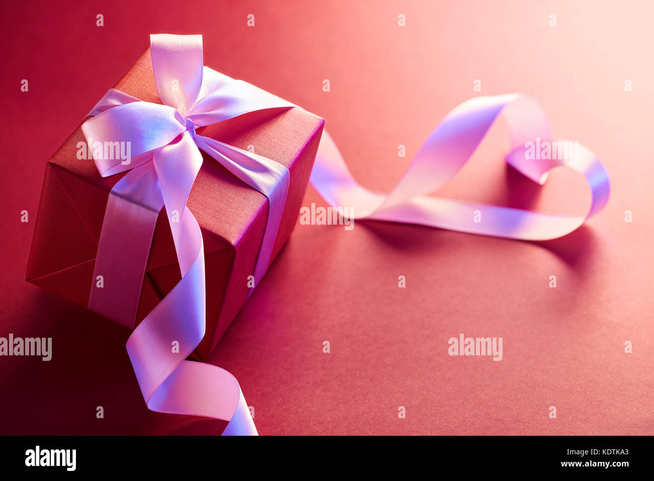 Gift box with heart shape ribbon on red background Stock Photo - Alamy