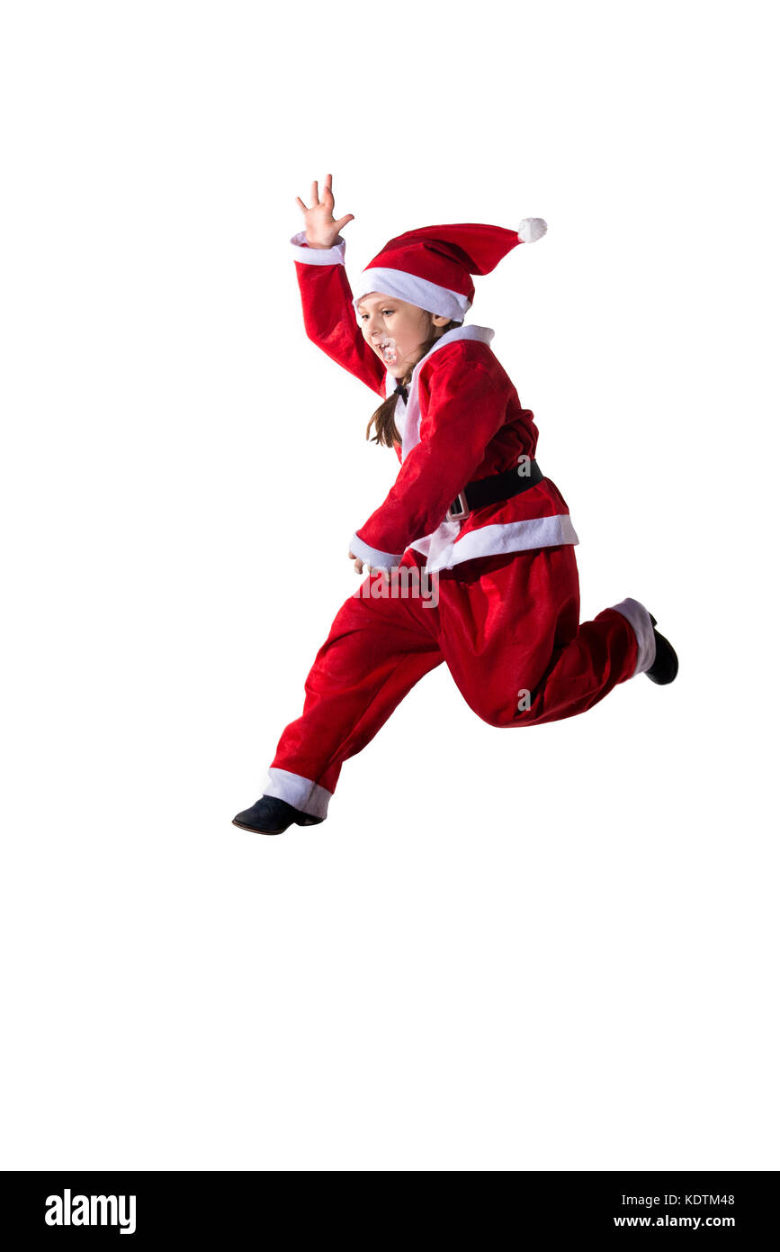 Little caucasian girl dressed as Santa Claus jumping on white ...