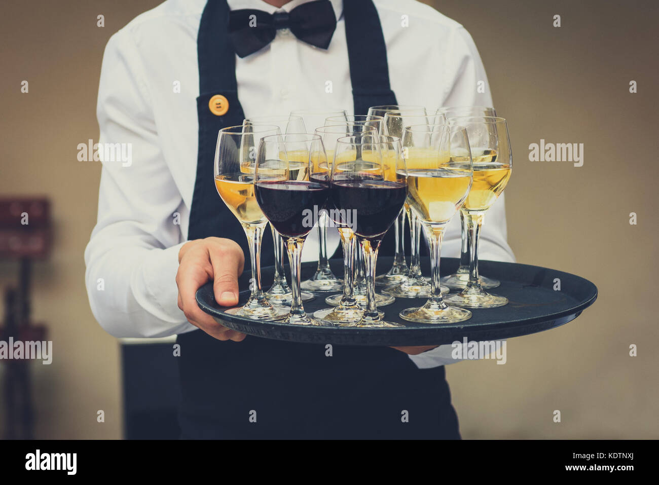 Professional waiter in black uniform serving red and white wine ...