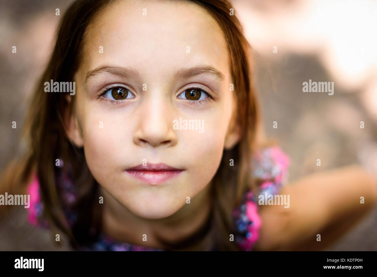 Portrait of little girl looking up at the parent outdoors. A child is ...
