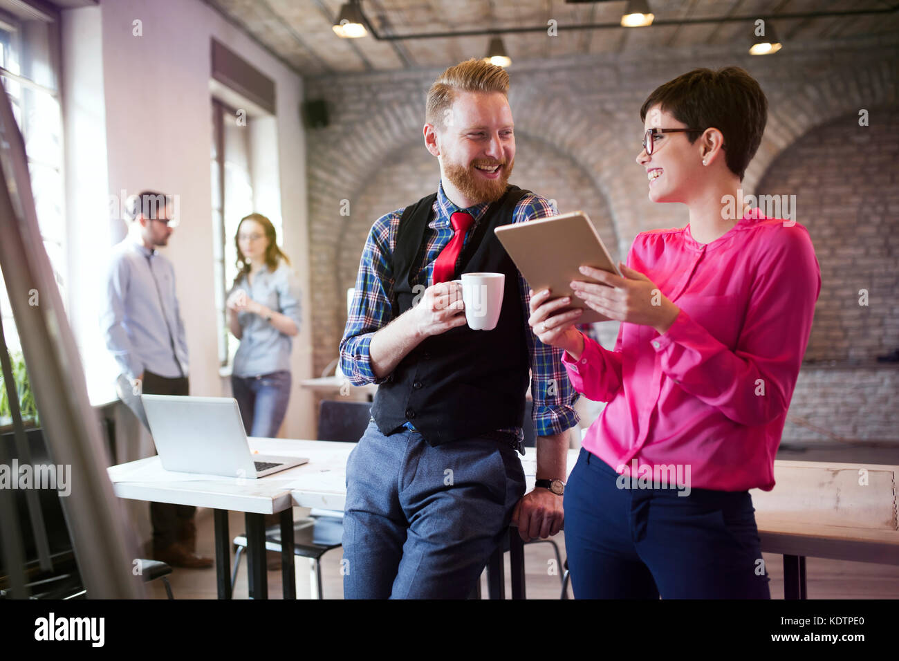 Young attractive designers talking and looking at digital tablet Stock ...